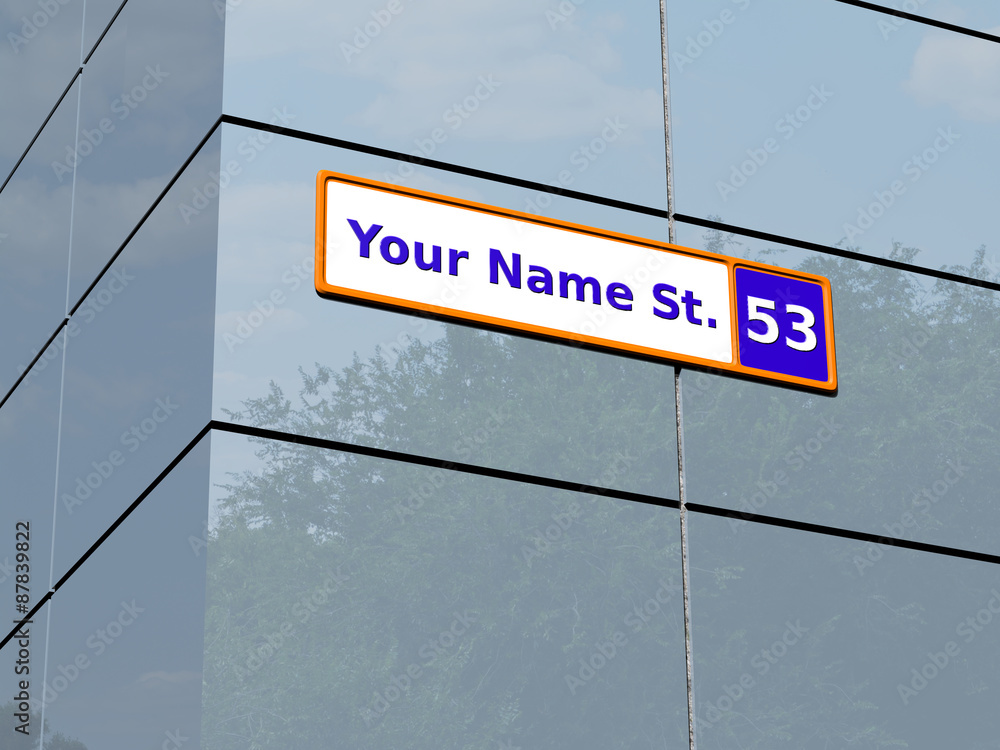 Generic street name plate attached to a glossy wall at the corner with ...