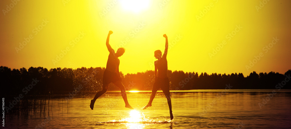 Glückliche junge Menschen laufen und springen am See beim ...