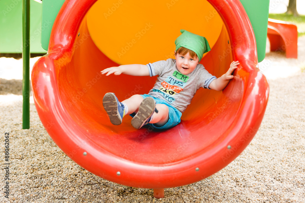 Kleiner Junge spielt freudig auf einer Rutsche Stock-Foto | Adobe Stock