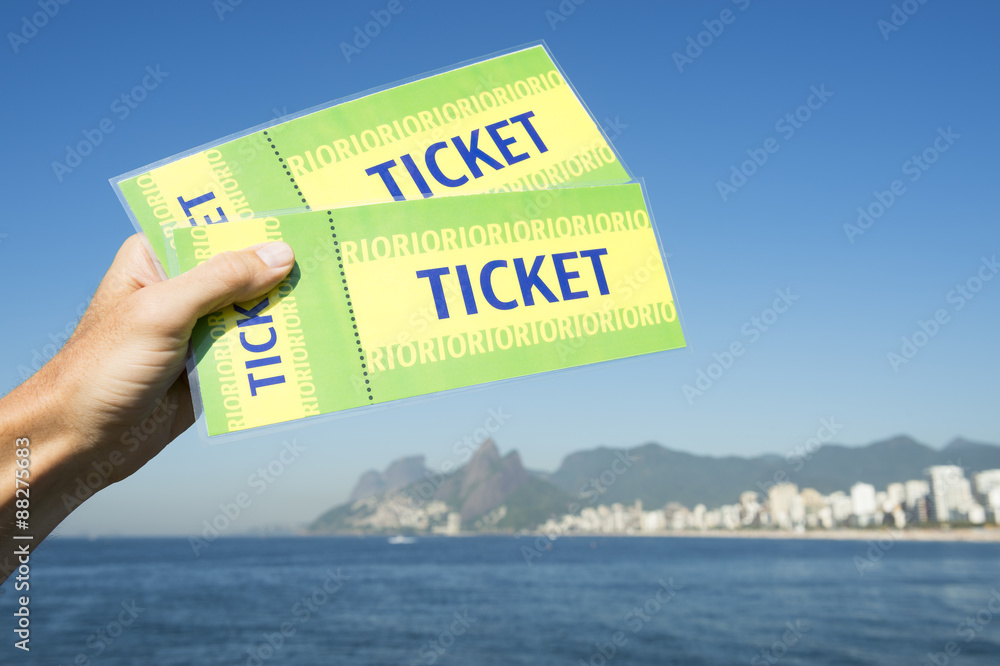 Hand holding pair of Brazil tickets in front of sea view Ipanema Beach ...