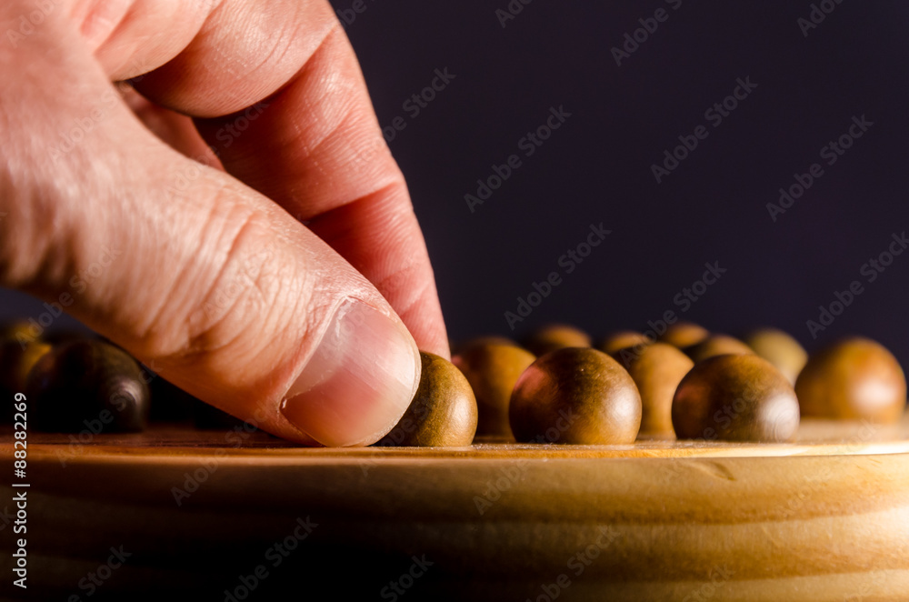 an human hand makes the first move on a solitaire board game, symbol of ...