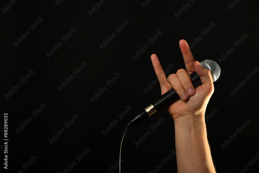 Foto de Hand with microphone and devil horns isolated on black do Stock ...