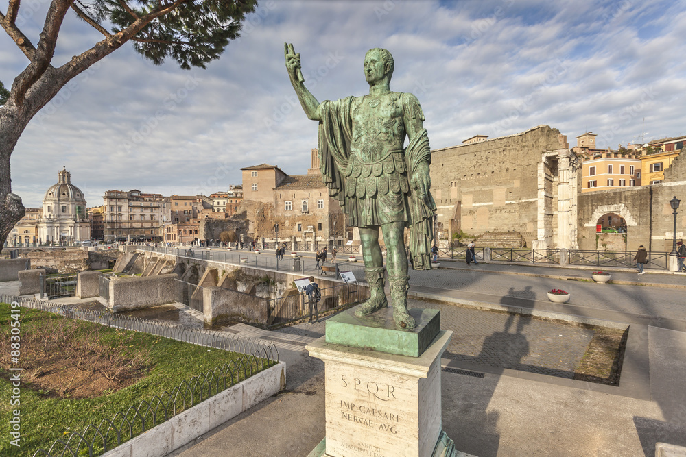 Bronze statue of the roman emperor Nerva with ruins of roman forum ...