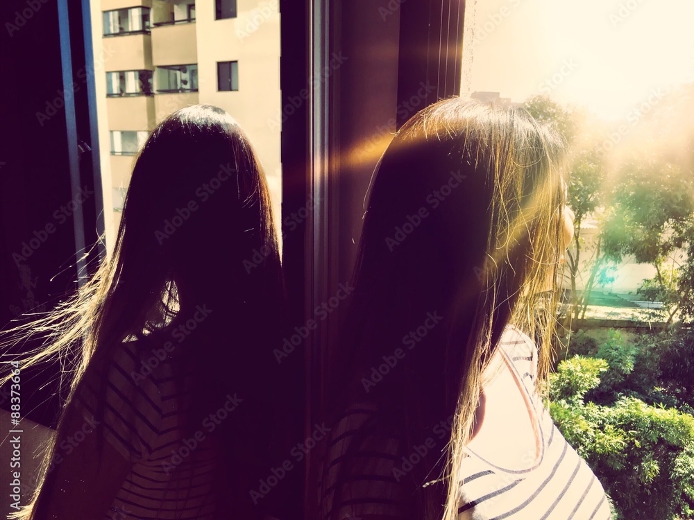Girl at the window looking the sun Stock Photo | Adobe Stock