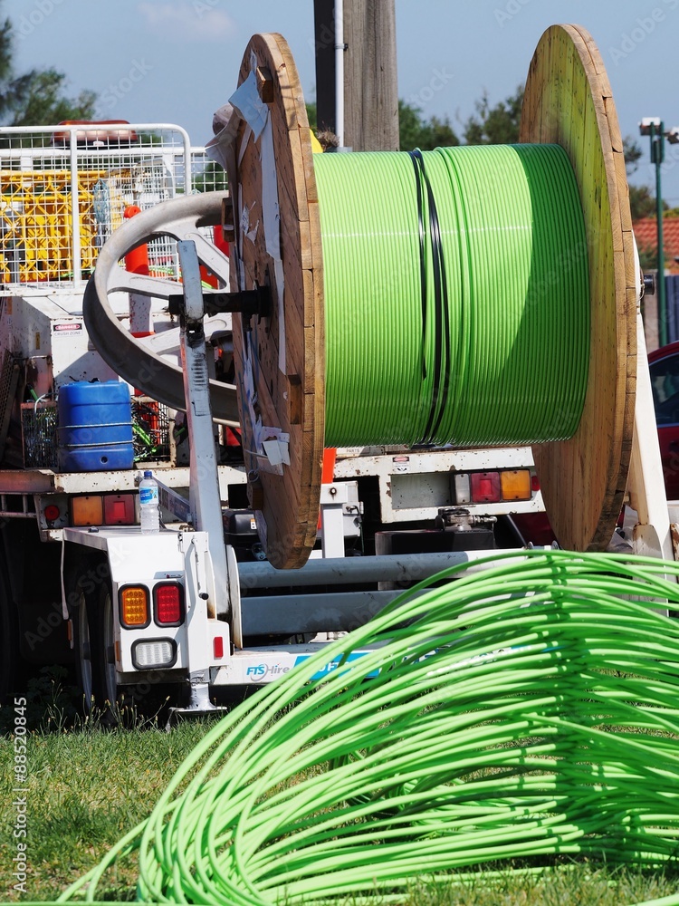 Green NBN fiber optic cable piled up behind an installation truck with ...