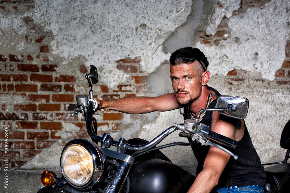 Foto de Tough guy with his bike in front of a brick wall do Stock ...
