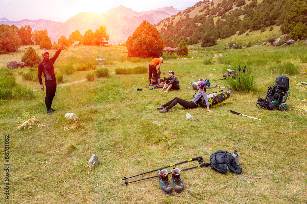 Hikers break on grassy lawn. Group tourists doing break male observing ...