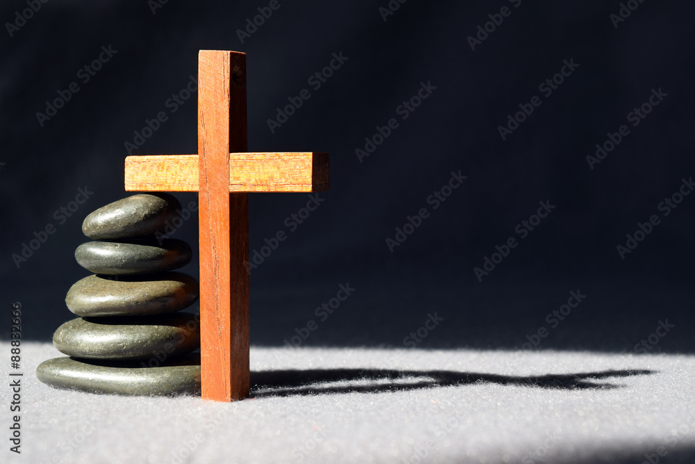 This shows a simple wooden cross standing next to a peaceful stack of ...