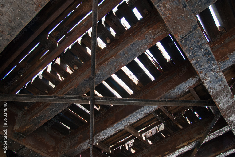 Underside of old railroad bridge showing rusty steel girders and train ...