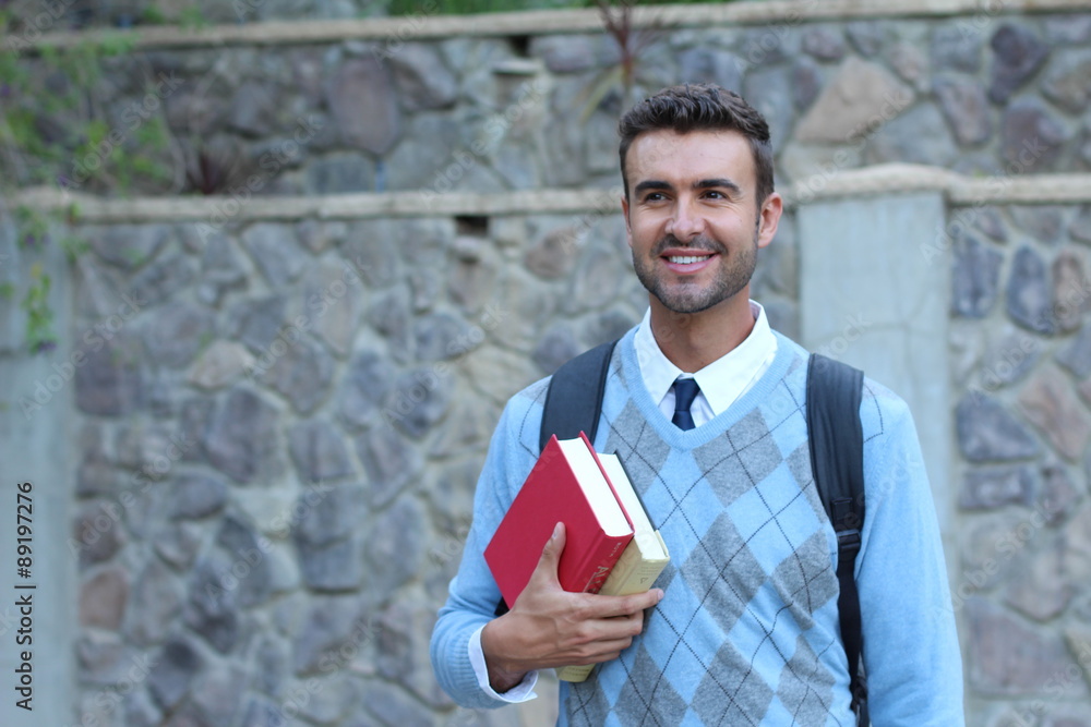 Enjoying university life. Handsome young British man holding books and ...