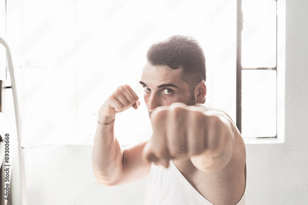 In a gym, a sports man in fighting stance, practical training box ...