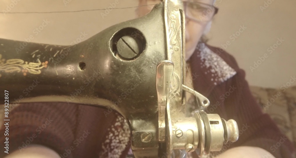grandmother sews a red flag on an old sewing machine of the Soviet ...