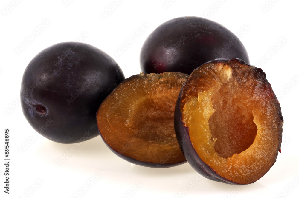 Prunes entières à côté d'une prune coupée en deux Photos | Adobe Stock