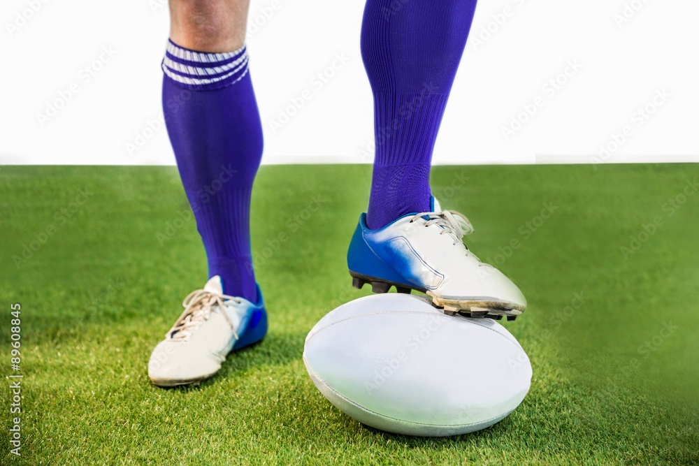 Rugby player posing feet on the ball Photos | Adobe Stock