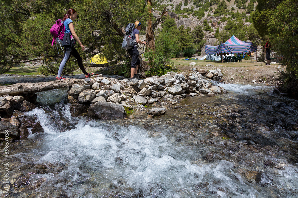 Hikers crossing river People walking on primitive handmade footbridge ...