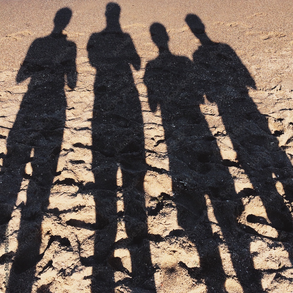 four men friends shadows on the sand beach sea Stock Photo | Adobe Stock
