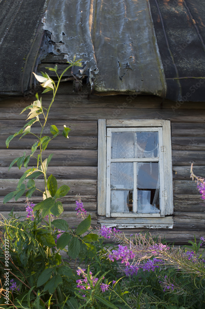 Window with broken glass and a leaky roof of an old rustic log home ...