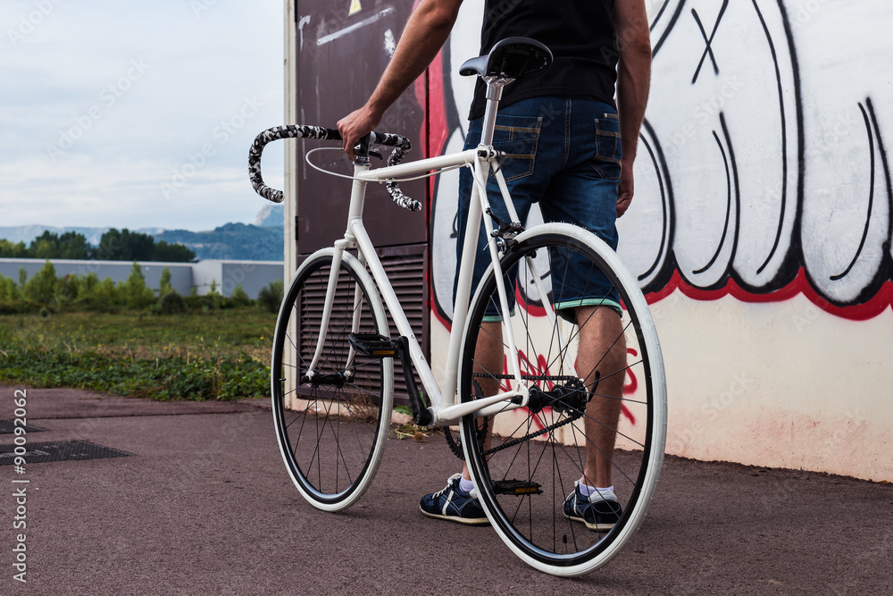 Young man with a fixie bike. Wall painted with a graffiti Stock Photo ...