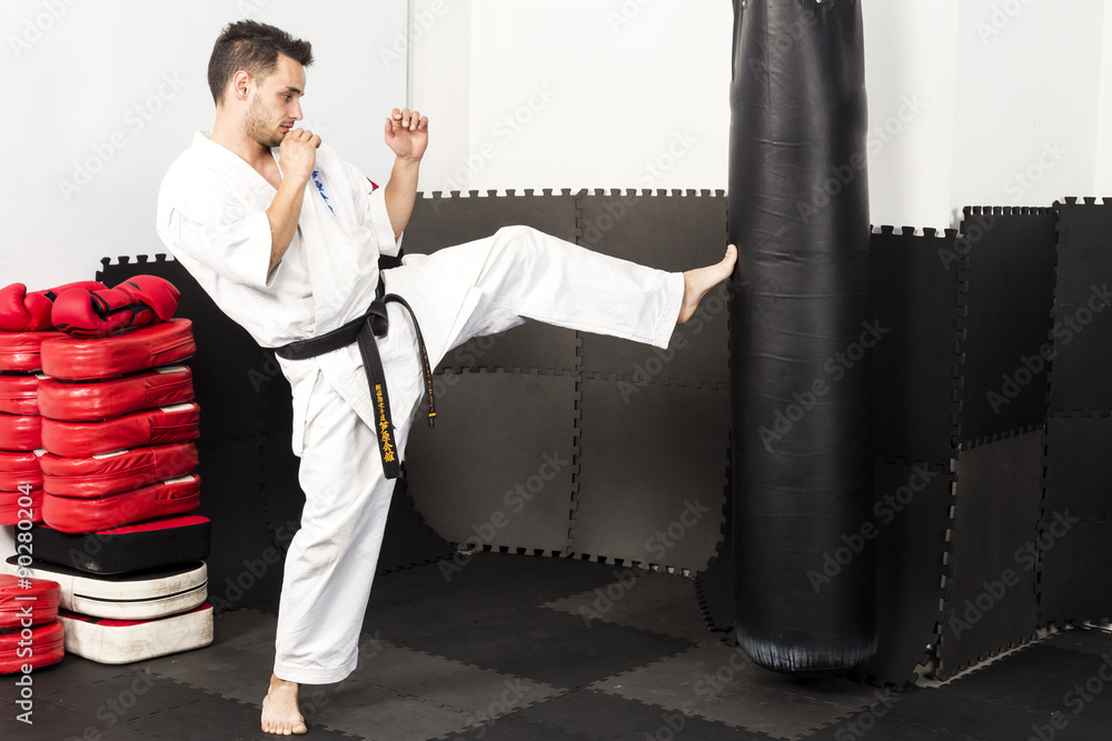 Foto Stock Athletic karate fighter giving a forceful foot kick to a ...