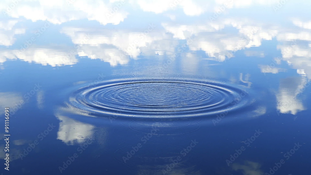 circles flow along surface of water, in water reflects sky with clouds ...
