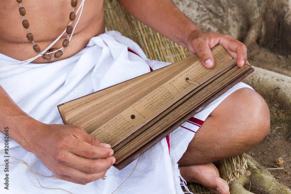 A young Indian man reads an ancient Hindu text under a banyan tree in ...