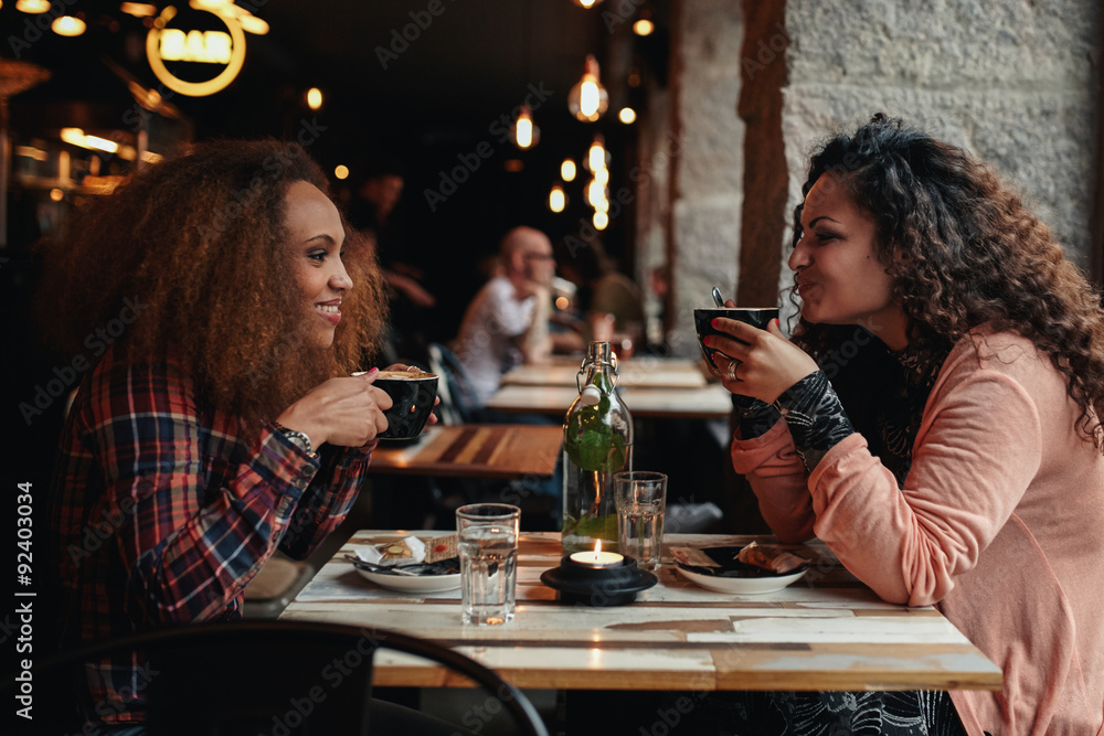 Two women talking and drinking coffee in a cafe Stock Photo | Adobe Stock