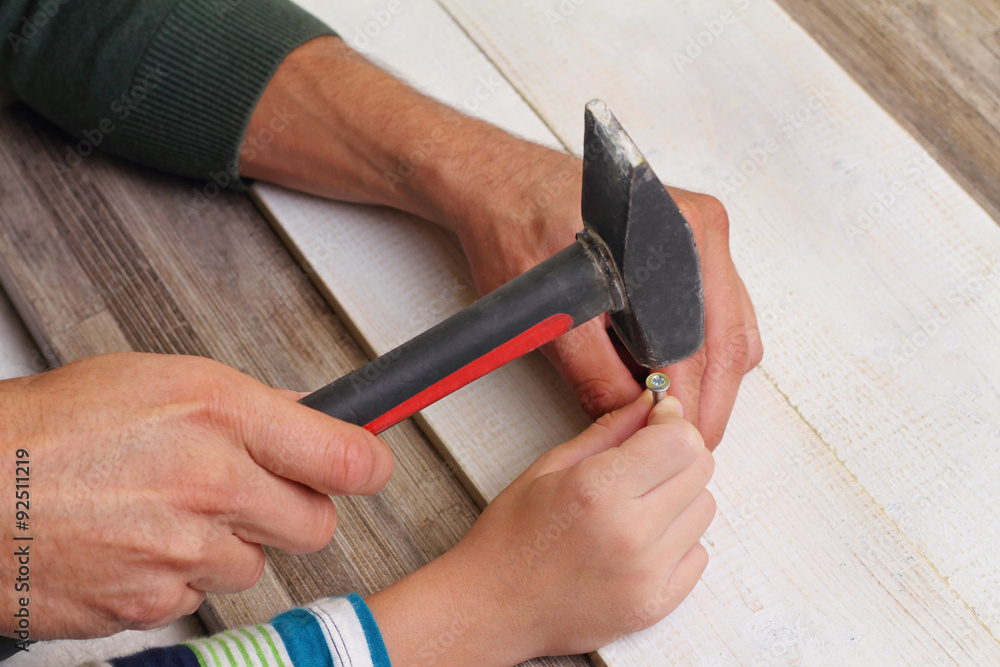 Father and son using hammer and nail spike. Boy helping his dad with ...