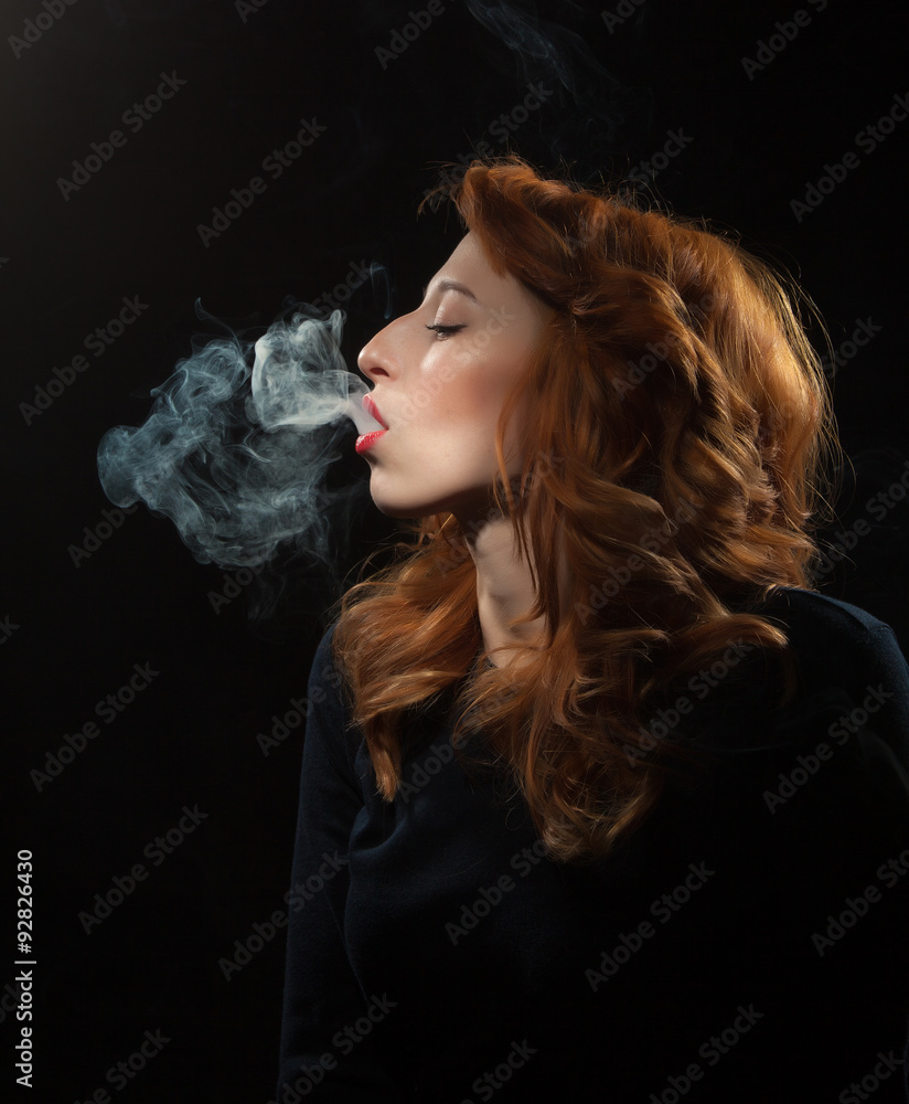 Portrait of a beautiful woman who smokes on a black background. Stock ...