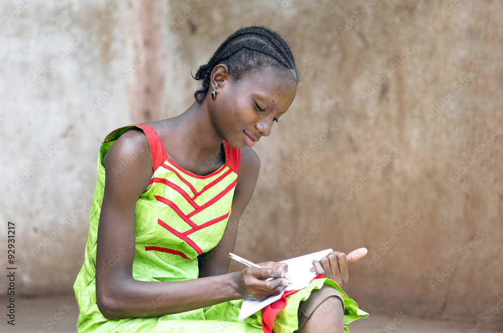 Gorgeous Black African Girl writing and drawing on her exercise book in ...