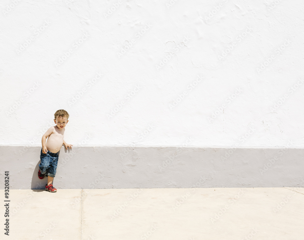 Shirtless little boy leaning against a wall Stock Photo | Adobe Stock