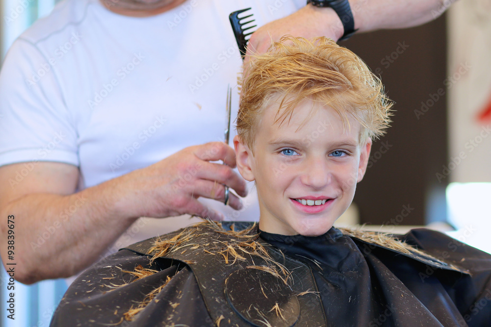Teenage boy having a haircut in a salon. Cute caucasian teenager ...