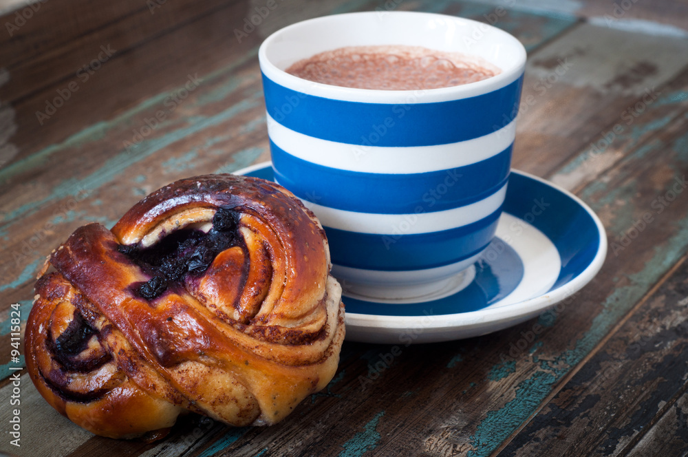 Swedish cinnamon berry bun served on a rustic wooden table with a cup ...