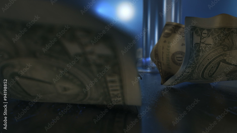 An slow pan across an isolated stripper pole on a stage lit by ...