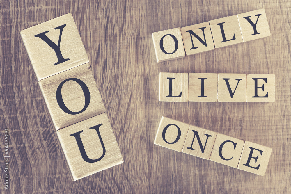 You Only Live Once (YOLO) message formed with wooden blocks. Cross ...