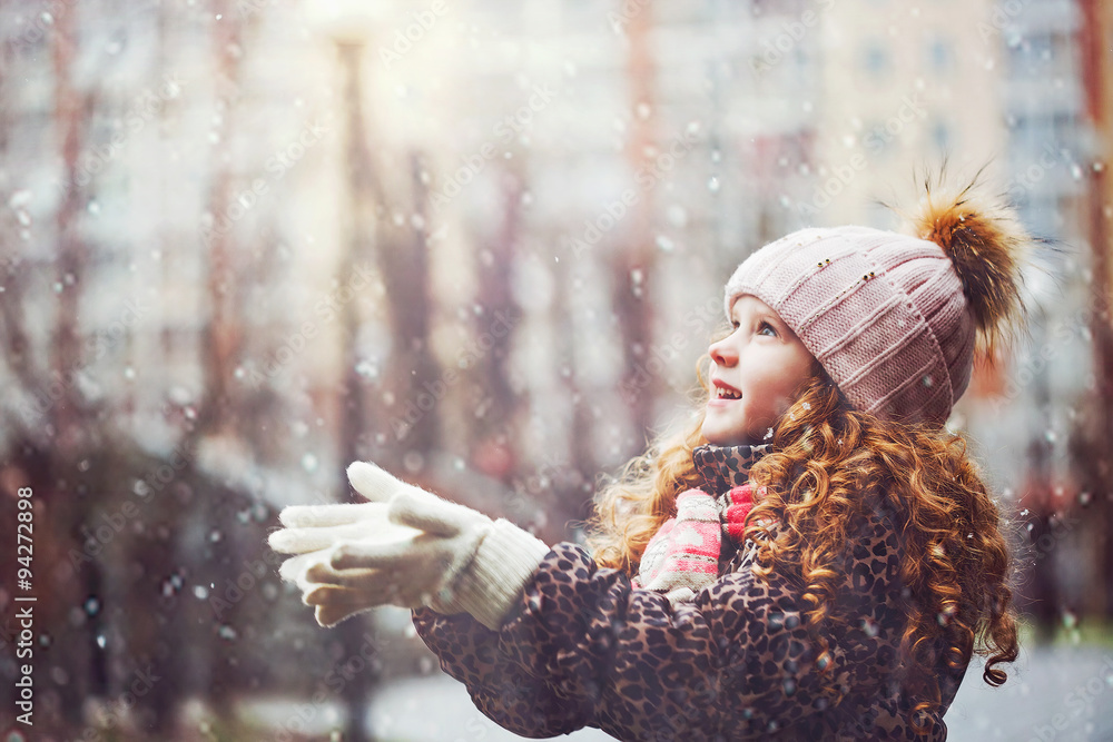 Cute little girl stretches her hand to catch falling snowflakes. Stock ...