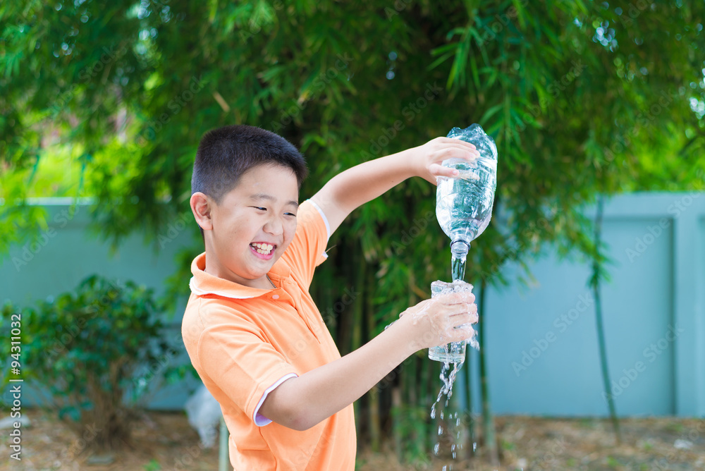 Poster Asian boy pouring water into glass from bottle, – Wall Art ...