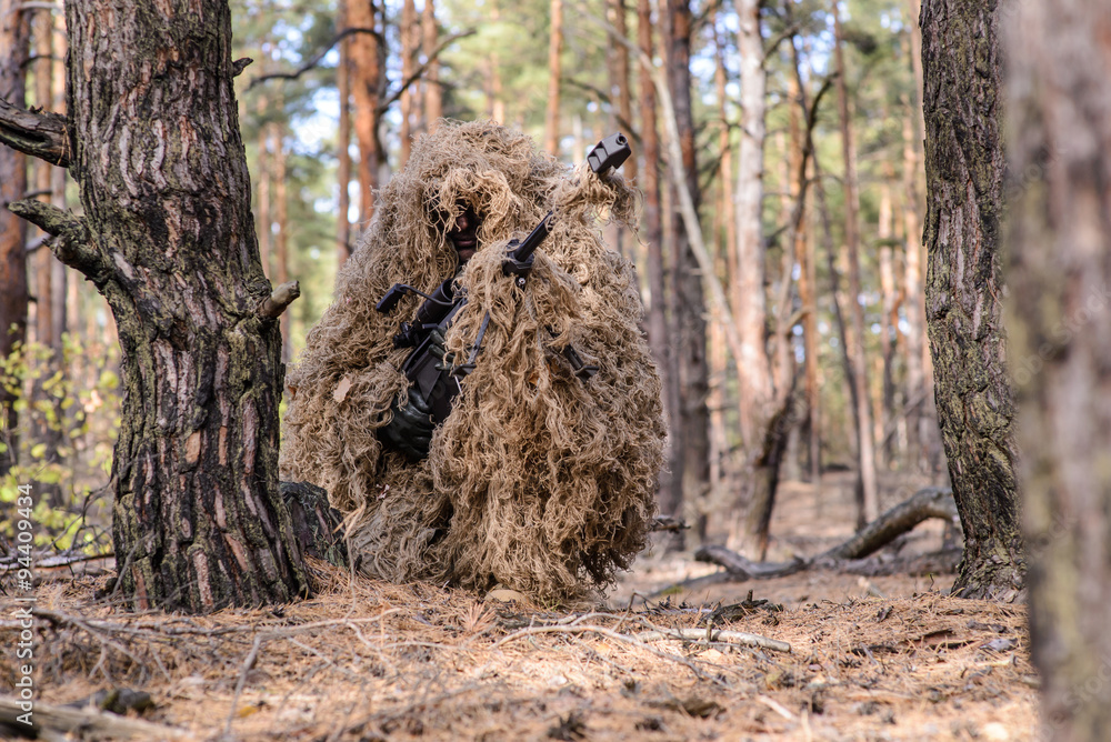 Sniper hide in the woods/Adult man in the uniform of a sniper hiding ...