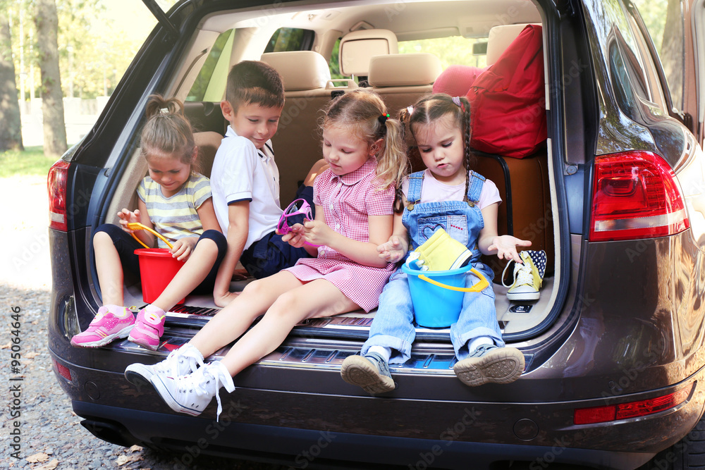 Three beautiful girls and boy sit on a car trunk and laughing Stock ...