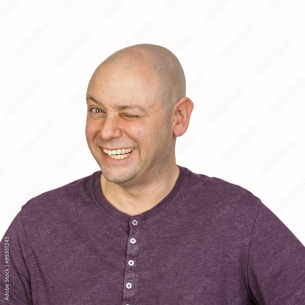 Big wink. Bald man in purple shirt in studio on white background give ...