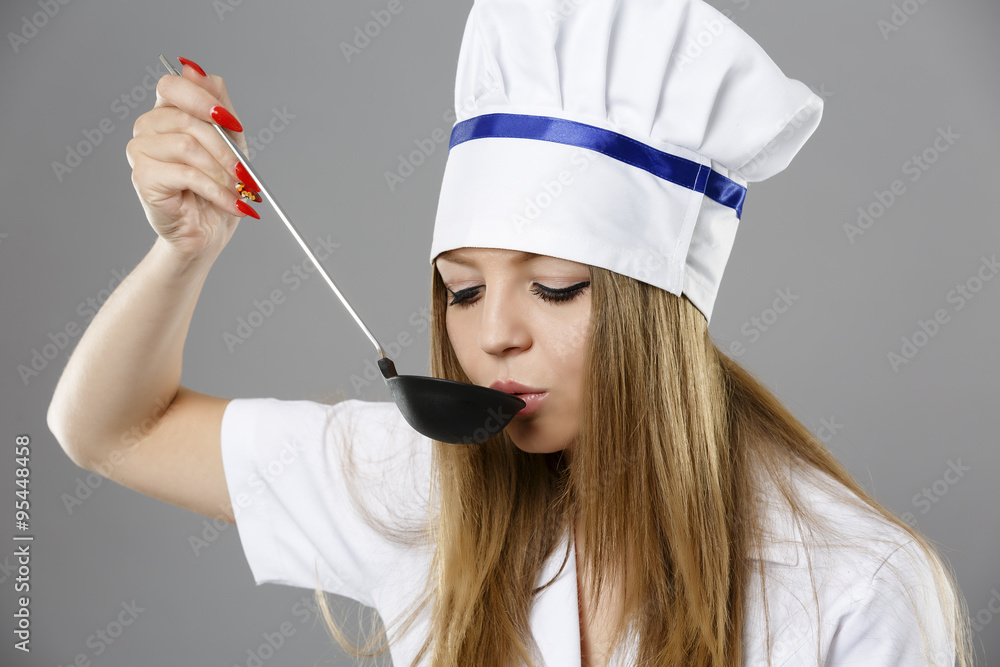 Woman chef holding a spoon and eating from spoon. On gray backgr Stock ...