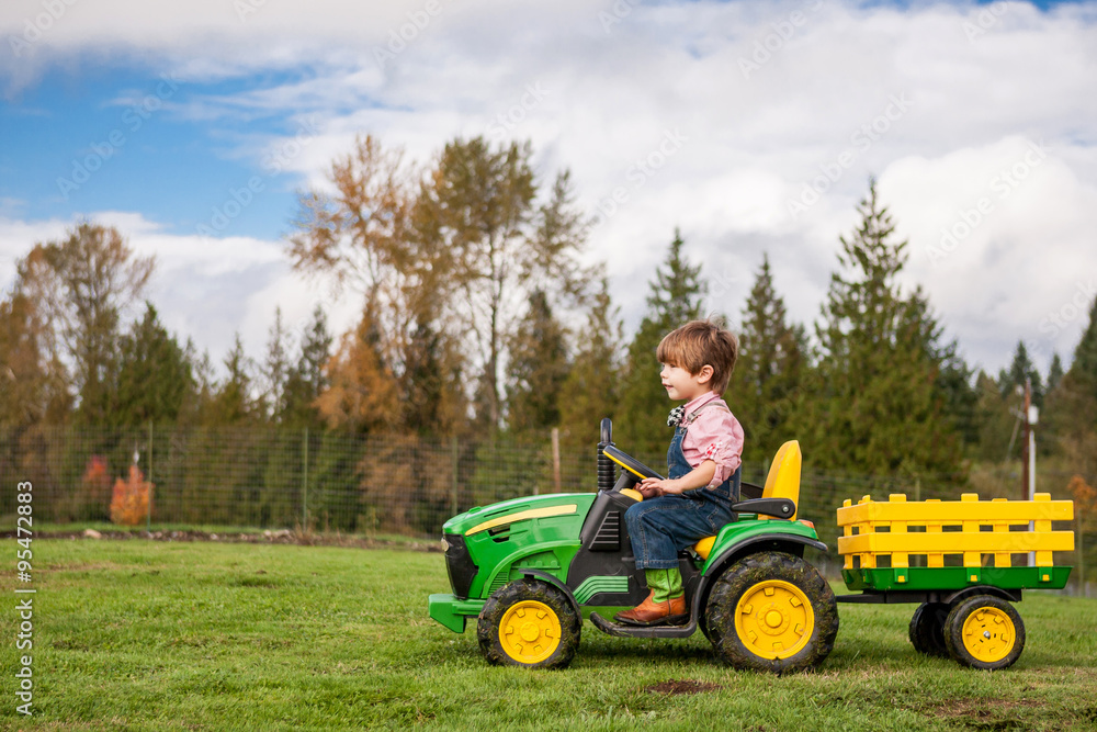 Boy driving a toy tractor Stock Photo | Adobe Stock