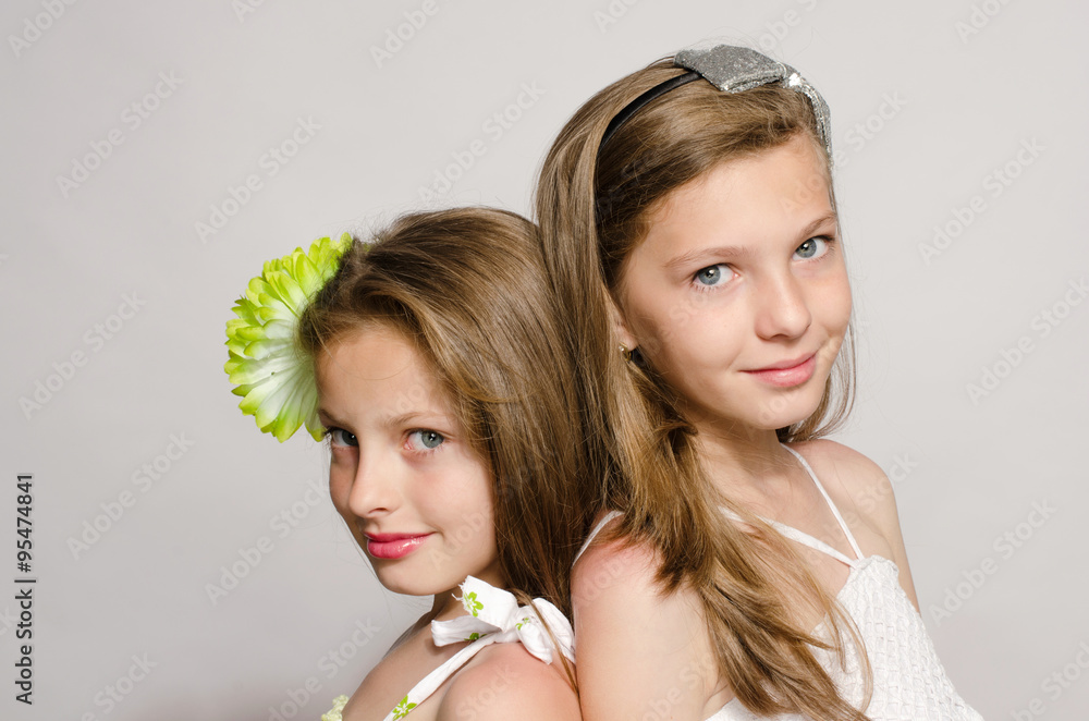 Two young girls staying back to back, sisters having fun, little sister ...