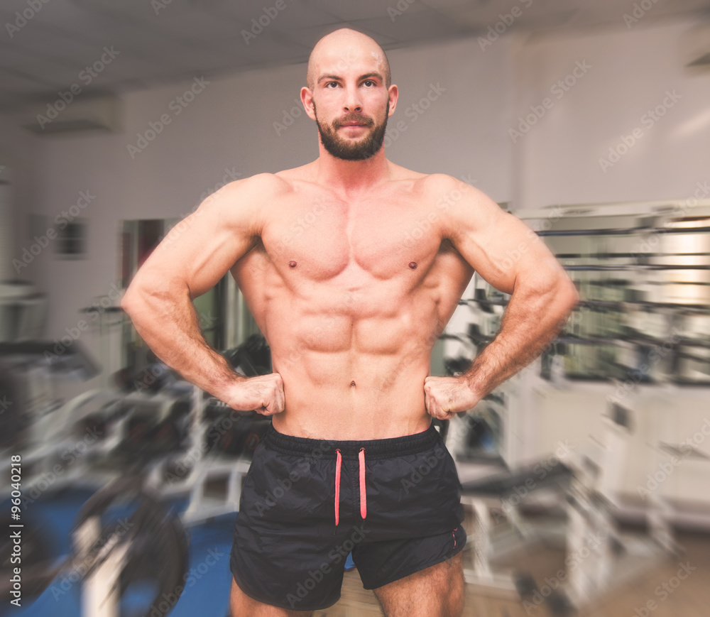 Man showing off his muscles at the gym with soft vintage filters ...