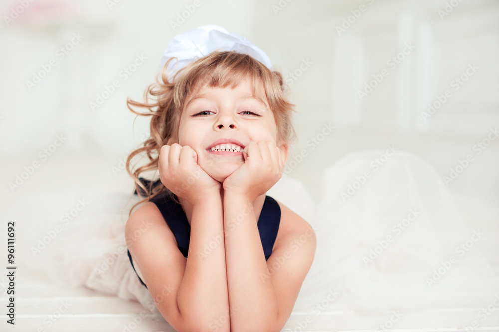 Smiling Cute Kid Girl 4 5 Year Old Lying On White Wooden Floor In Room smiling-cute-kid-girl-4-5-year-old-lying-on-white-wooden-floor-in-room