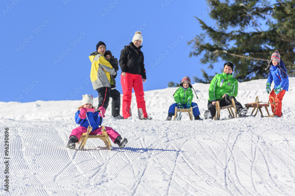 Familie beim Rodeln im Winter Stock-Foto | Adobe Stock