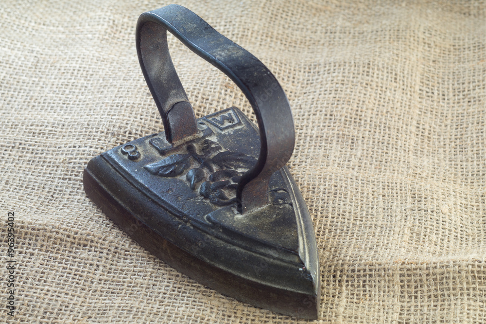 Ferro da Stiro antico in primo piano, sfondo tavolo in legno antico ...