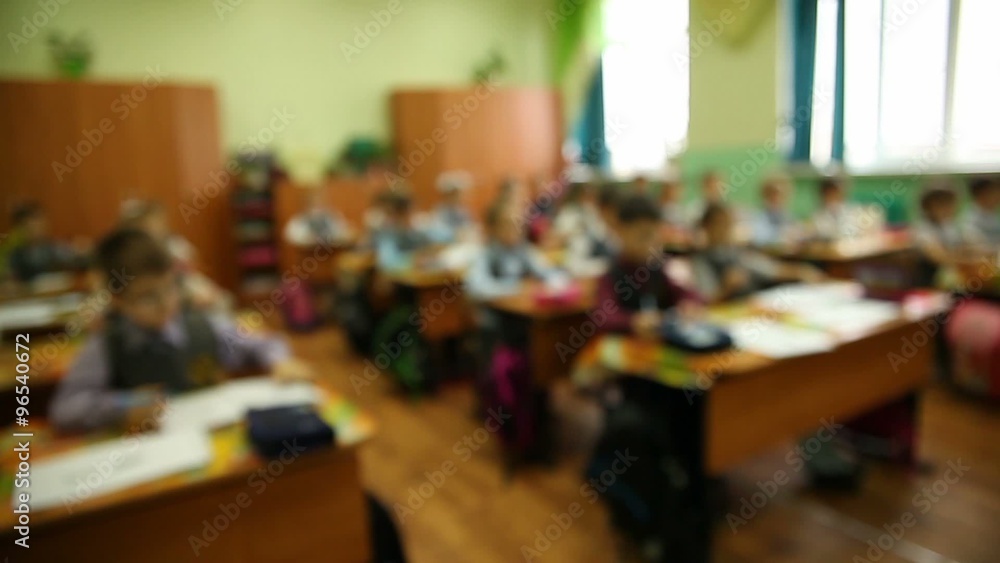 blurred background group of kids in a classroom at a school desk is ...