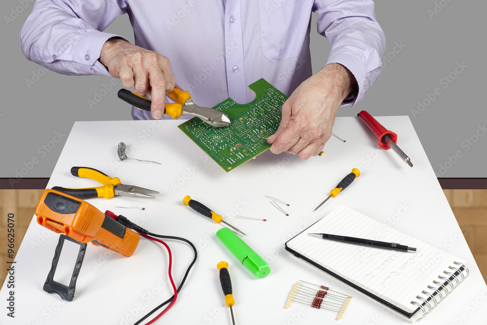 Electronic test engineer using side cutters to trim a soldered ...