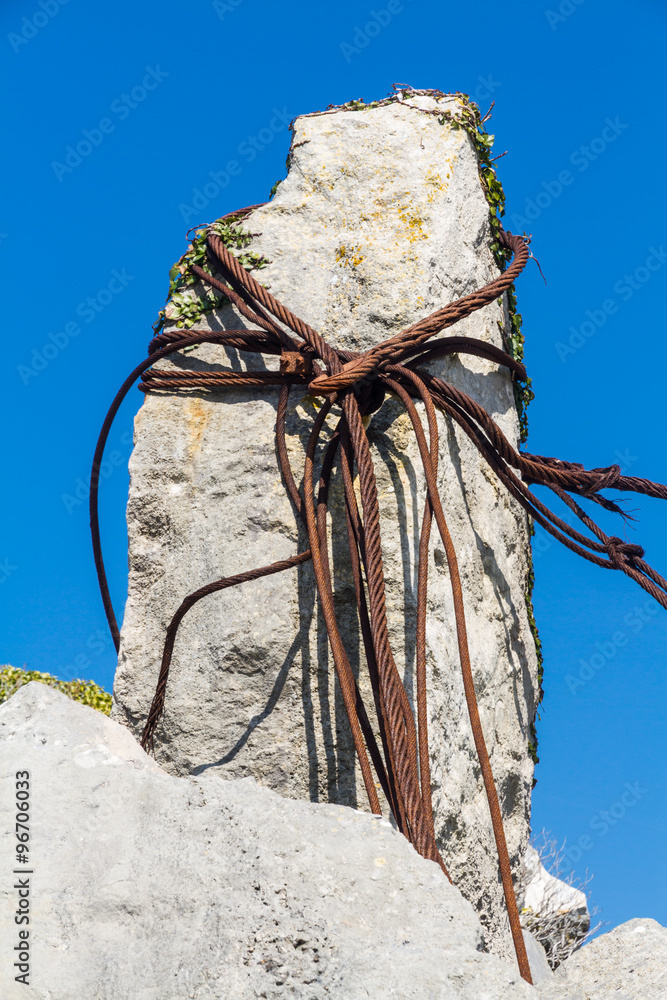 Rusty iron cables looped around limestone rock. Stock Photo | Adobe Stock