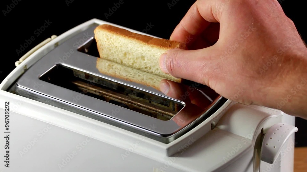 Hand putting white bread slices in toaster on black background Stock ...